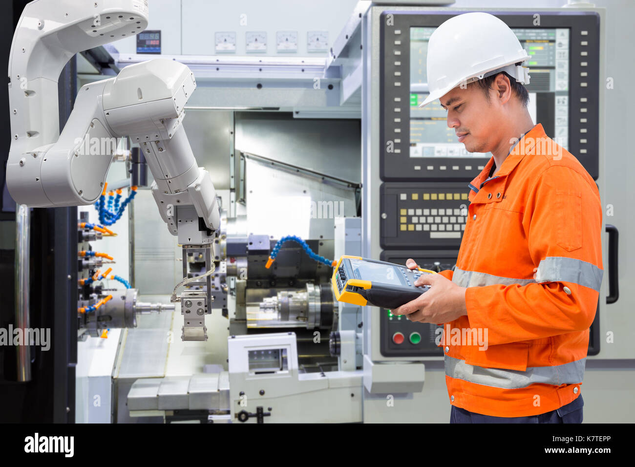 Maintenance engineer programing automated robotic with CNC machine in an industry Stock Photo ...