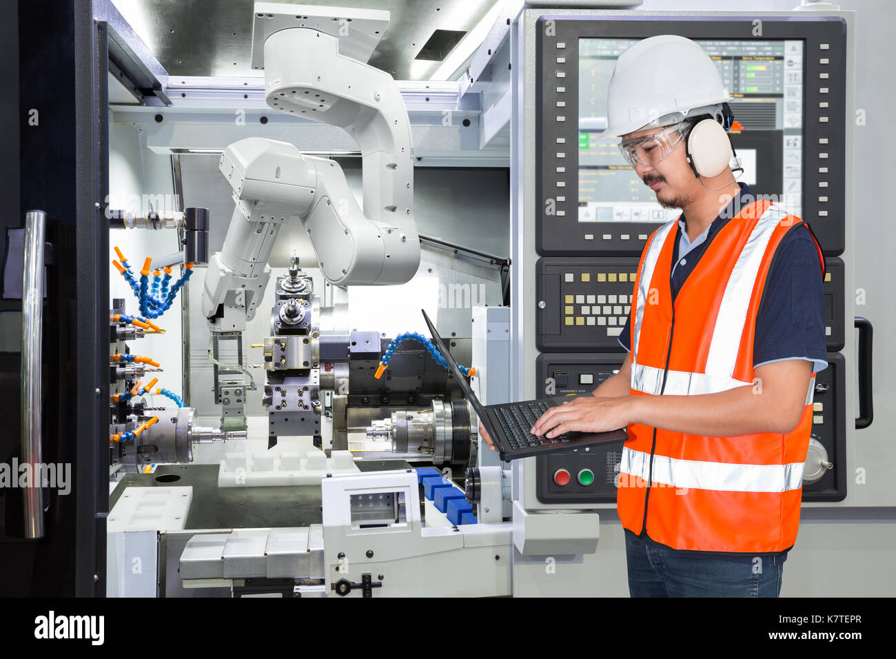 Engineer using laptop computer for maintenance automatic robotic arm with CNC machine in smart ...