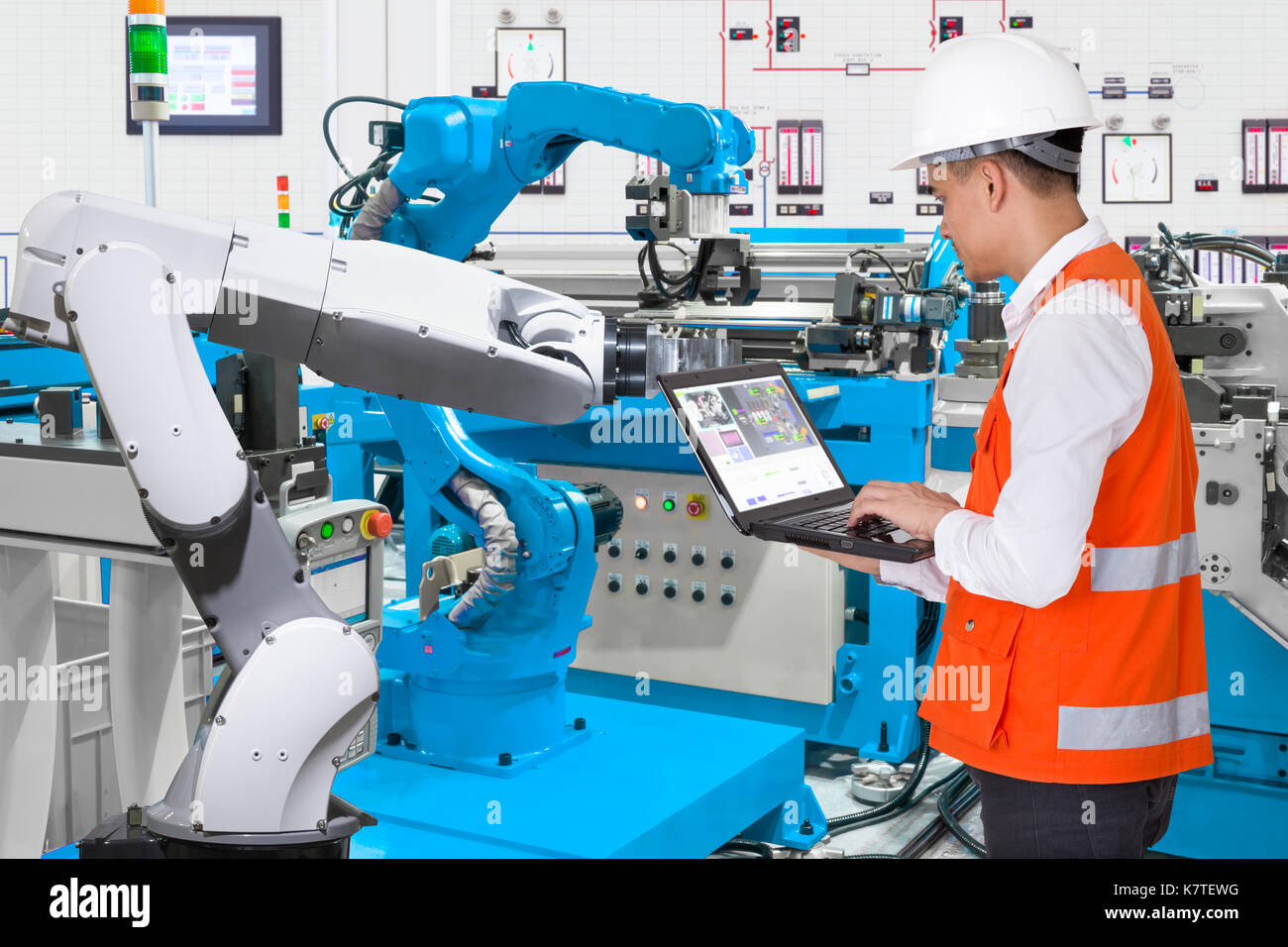 Engineer using laptop computer for maintenance automatic robotic hand machine tool at industrial ...