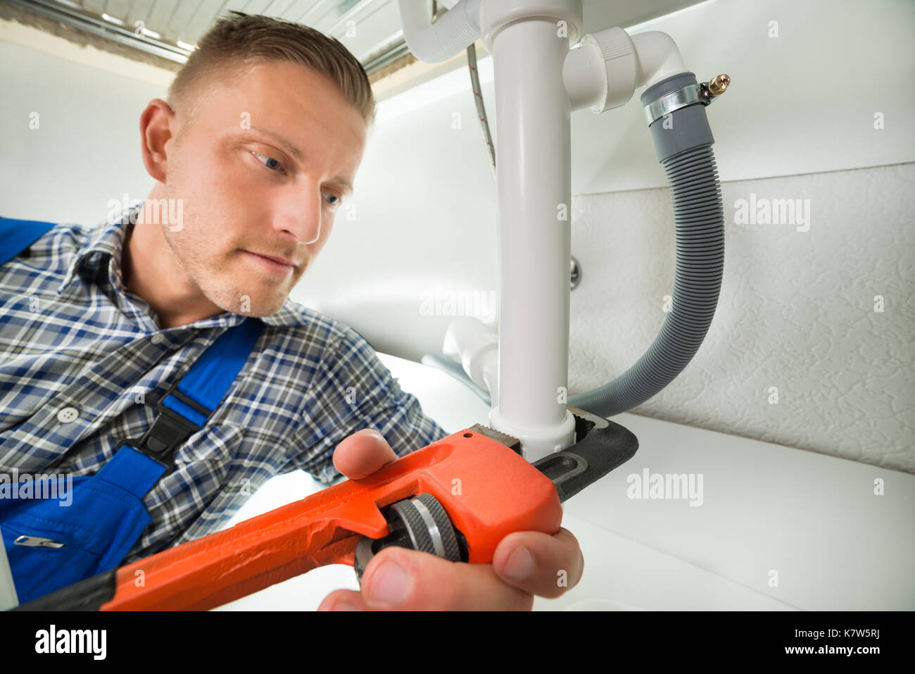 Close-up Of Male Plumber With Adjustable Wrench Repairing Sink Pipe ...