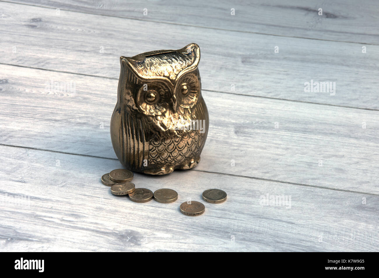 Brass owl money box with old one pound coins. In the UK the one pond ...