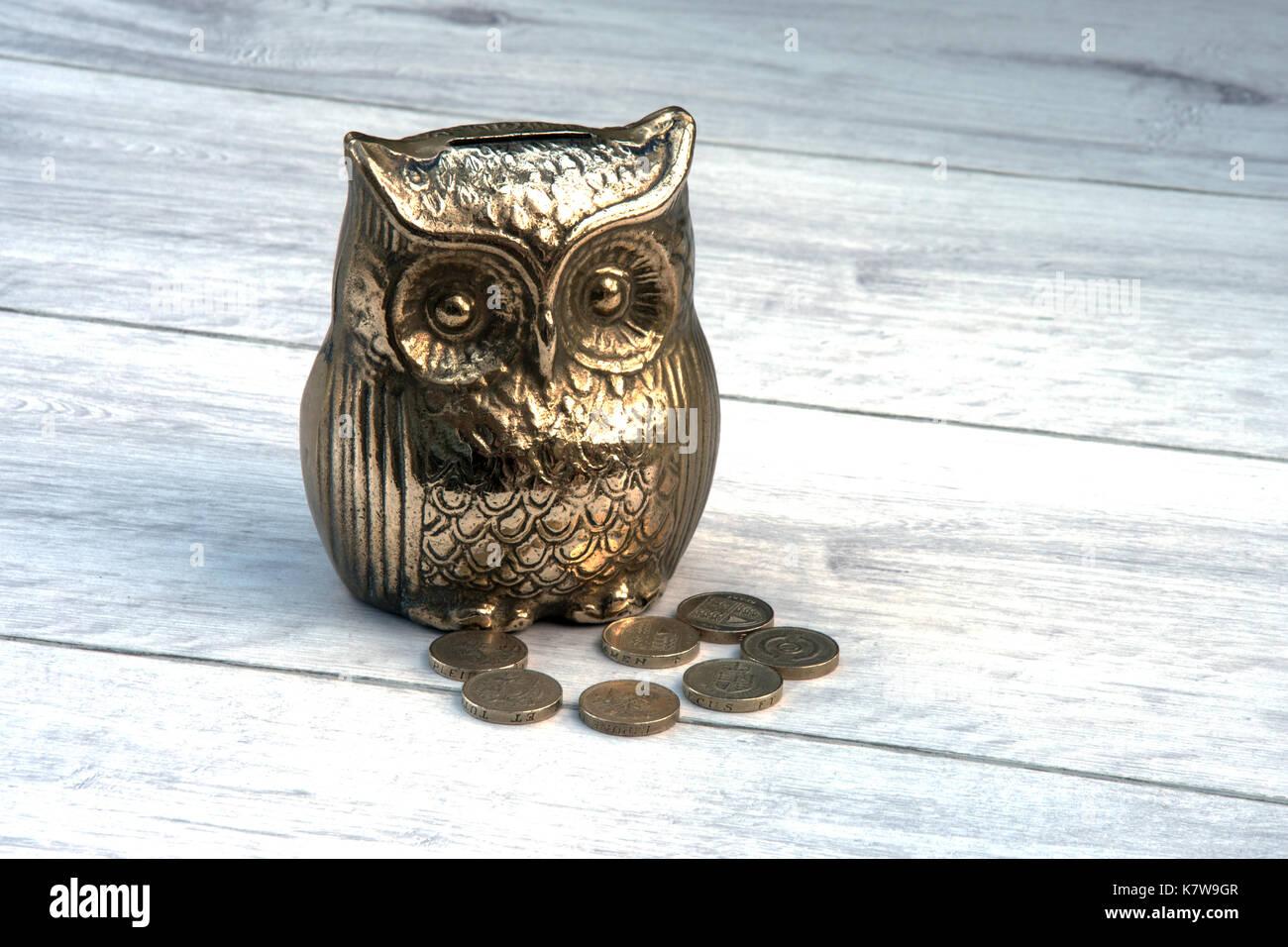 Brass owl money box with old one pound coins. In the UK the one pond ...