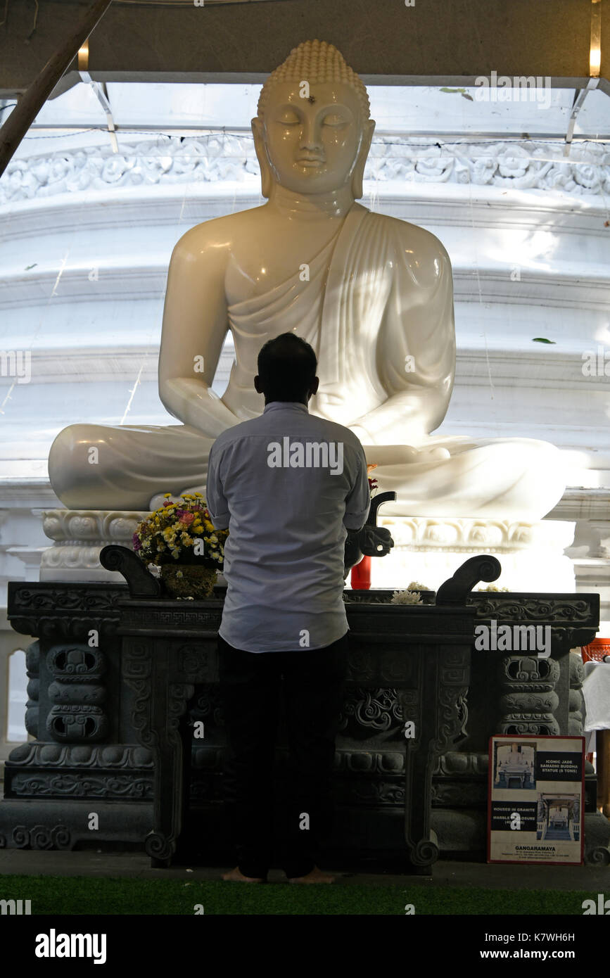A devotee praying in front of the white jade Samadhi Buddha statue on ...