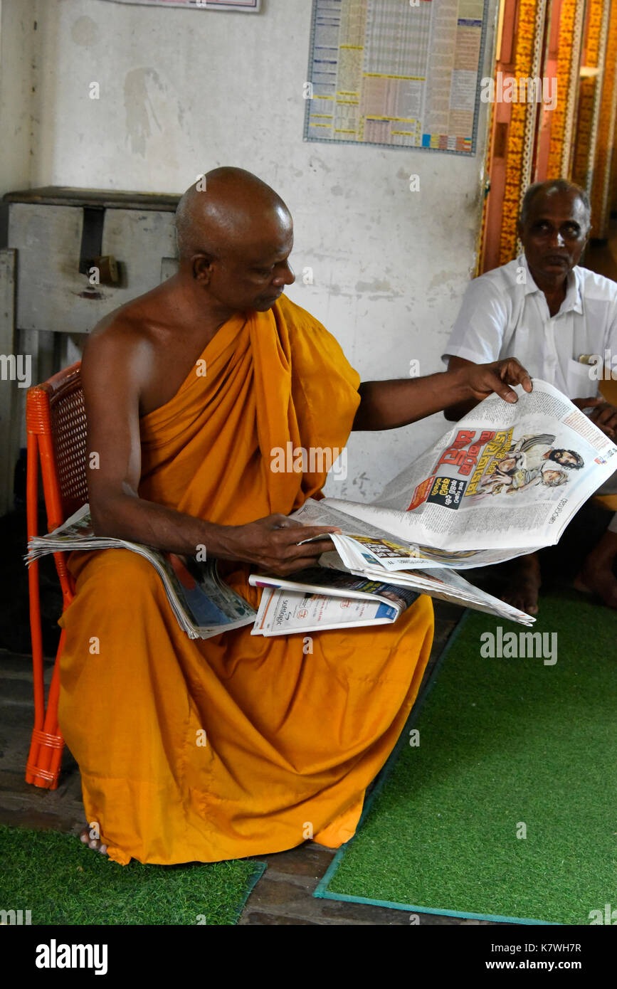 A Buddhist monk relaxing, reading his newspaper at the Gangaramaya ...