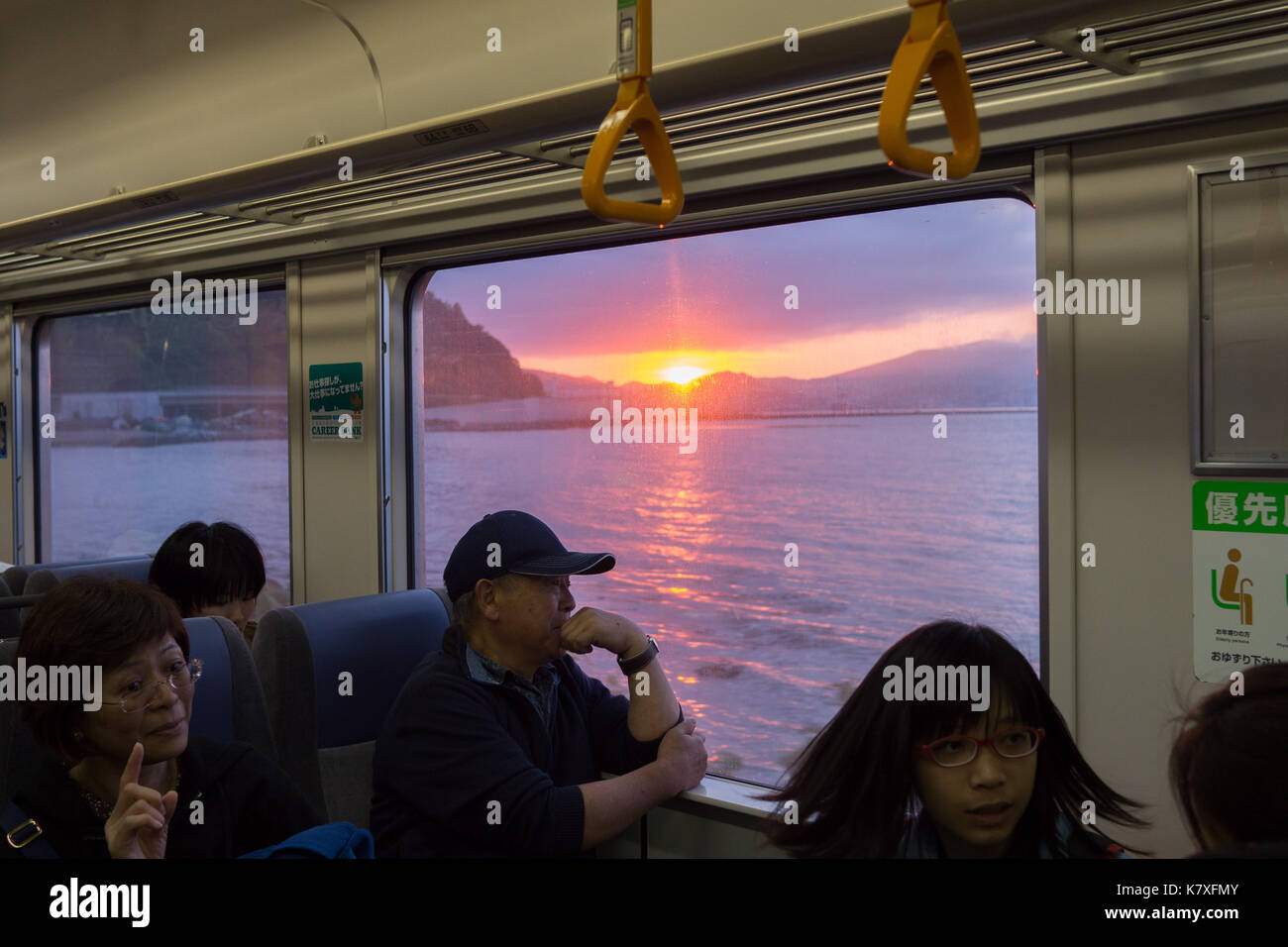 Setting sun shot through the window of a moving JR train with town in ...