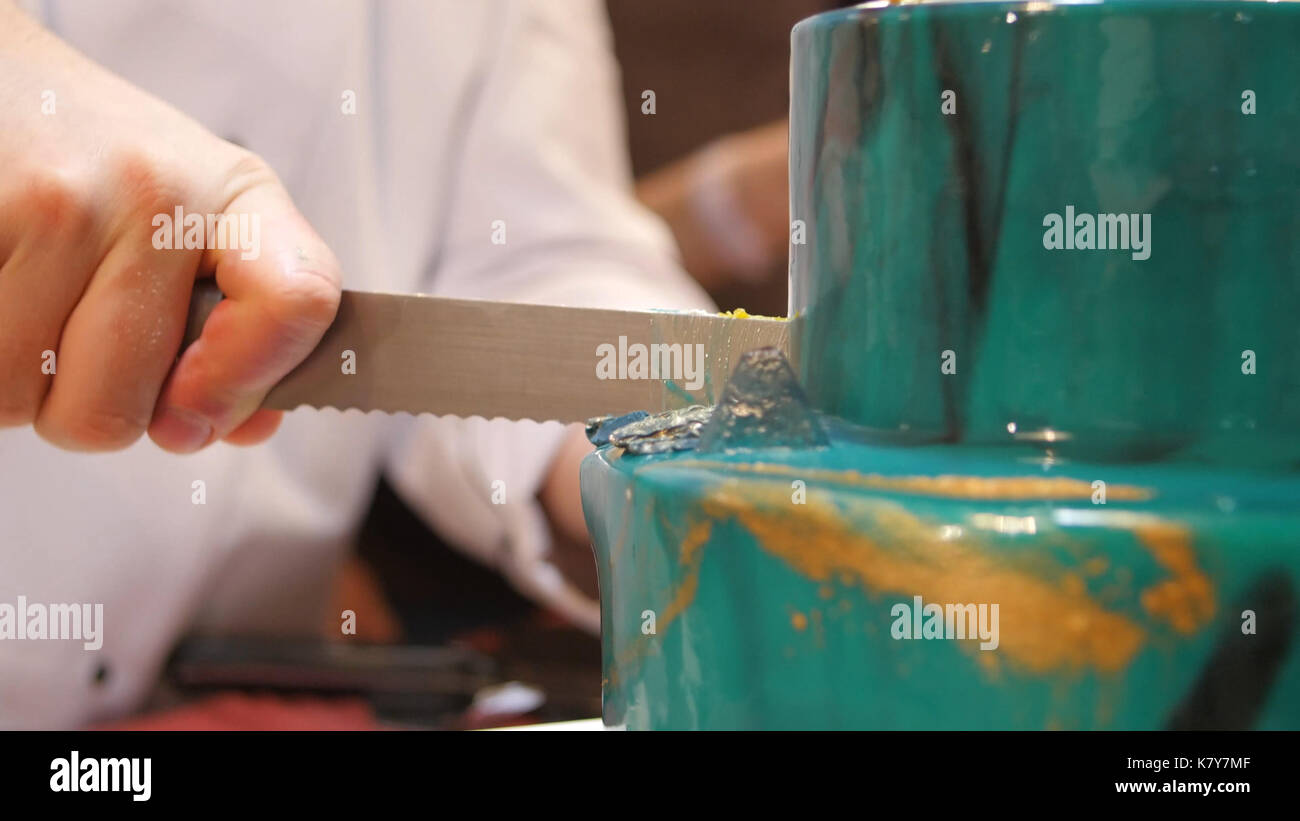 The pastry chef cut the cake with a long knife. Cut a turquoise cake ...