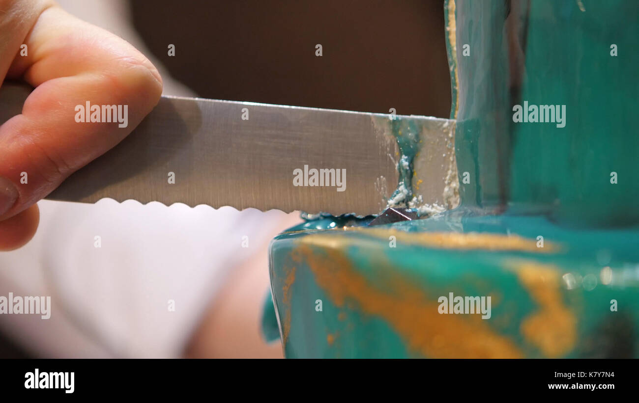 The pastry chef cut the cake with a long knife. Cut a turquoise cake ...