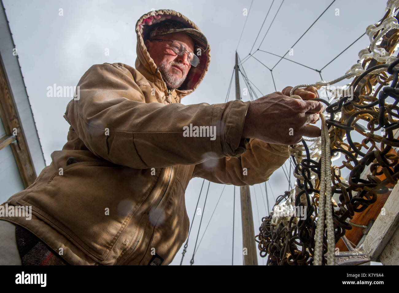 Captain attending to equipment aboard his oyster dredging skipjack ...