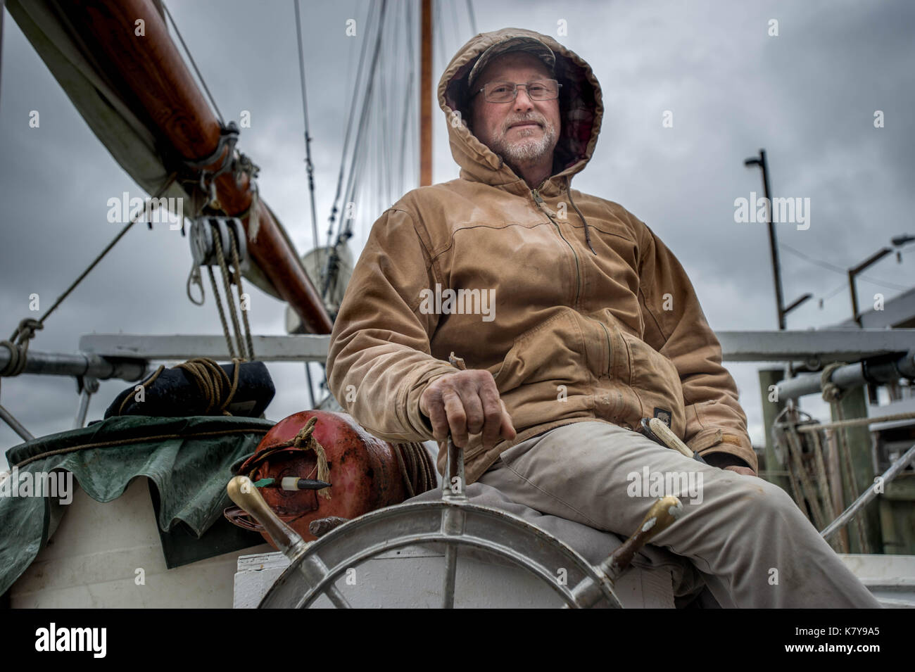 Captain Ted Daniels sitting at the ship's wheel aboard his oyster ...