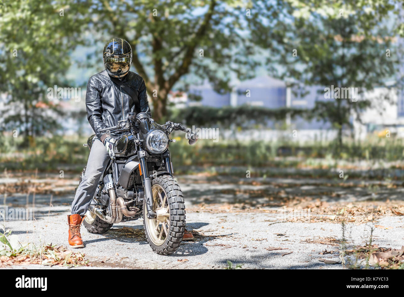 Cool looking motorcycle rider on custom made scrambler style cafe racer ...
