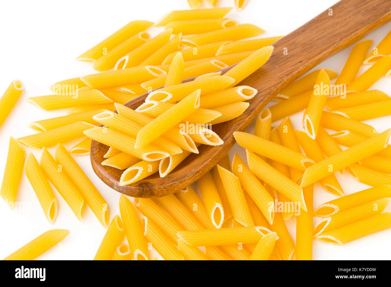 Dry, uncooked, raw penne pasta noodles in wooden spoon on white ...