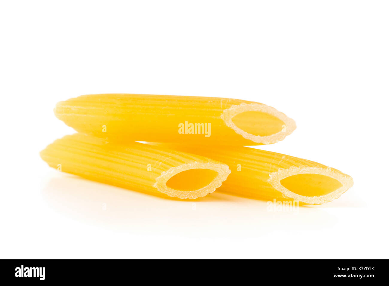Close up of three dried, raw, uncooked penne pasta over white ...