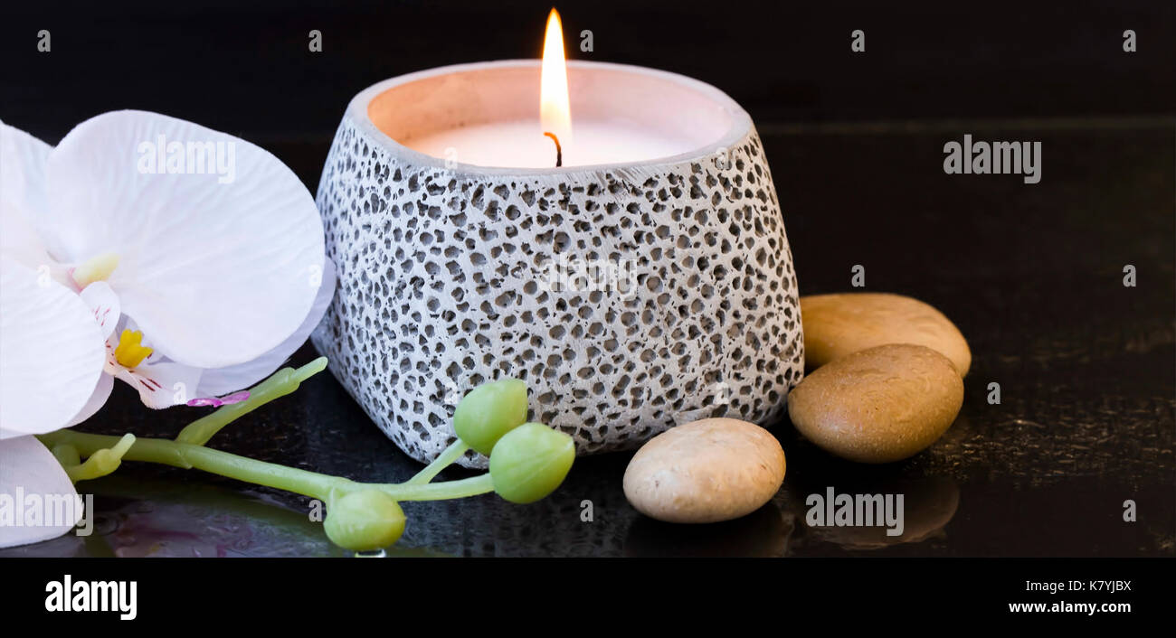 Spa candle setting with orchid and massage stones Stock Photo - Alamy