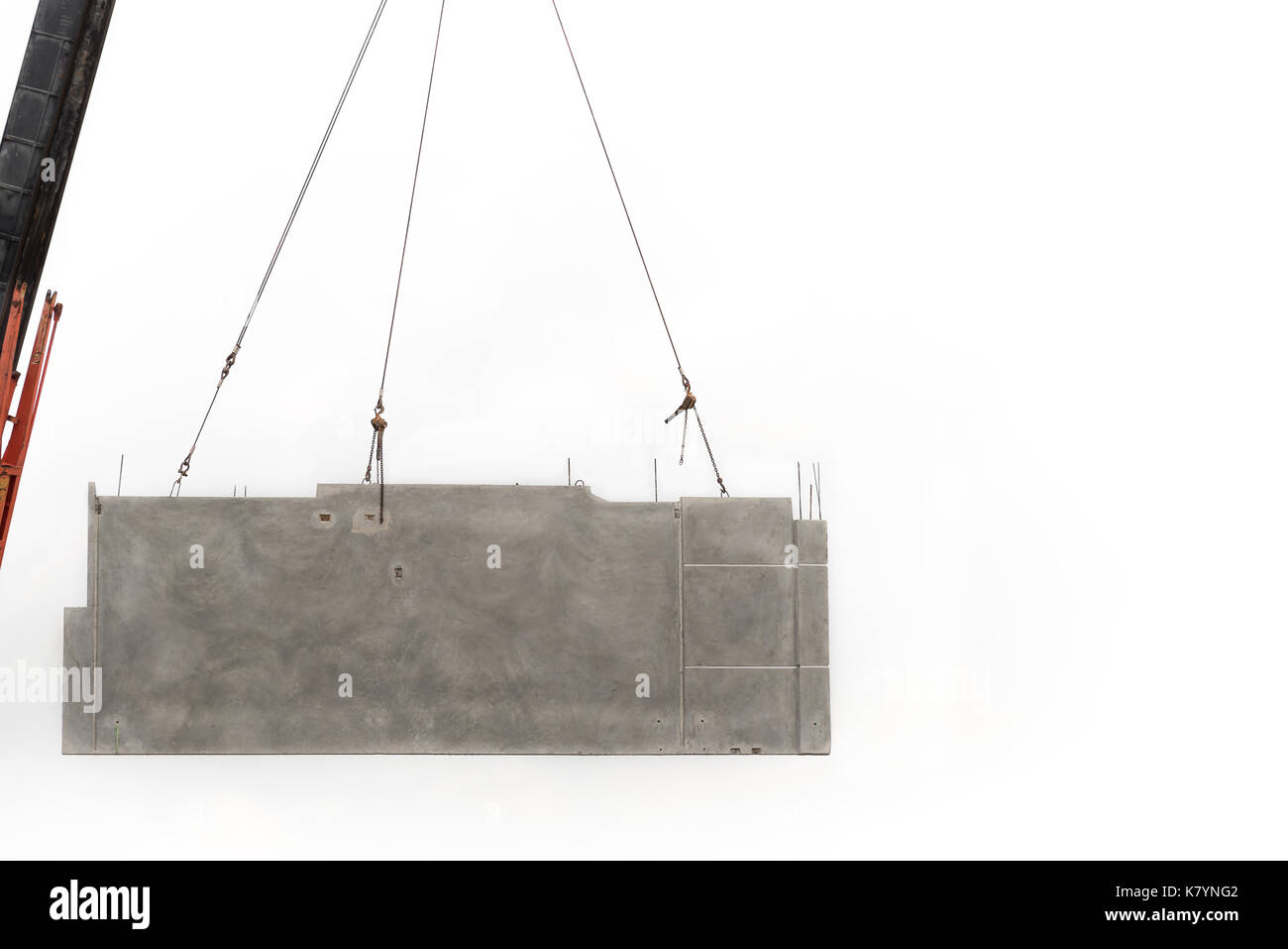 Construction site crane is lifting a precast concrete wall panel to ...