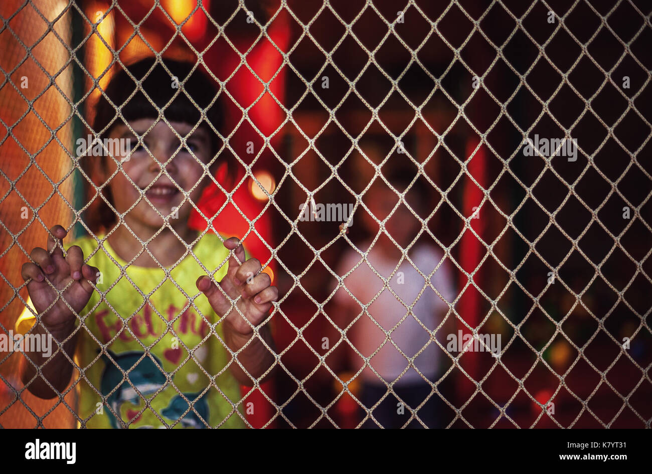 One small girl in kindergarten behind the rope net Stock Photo - Alamy