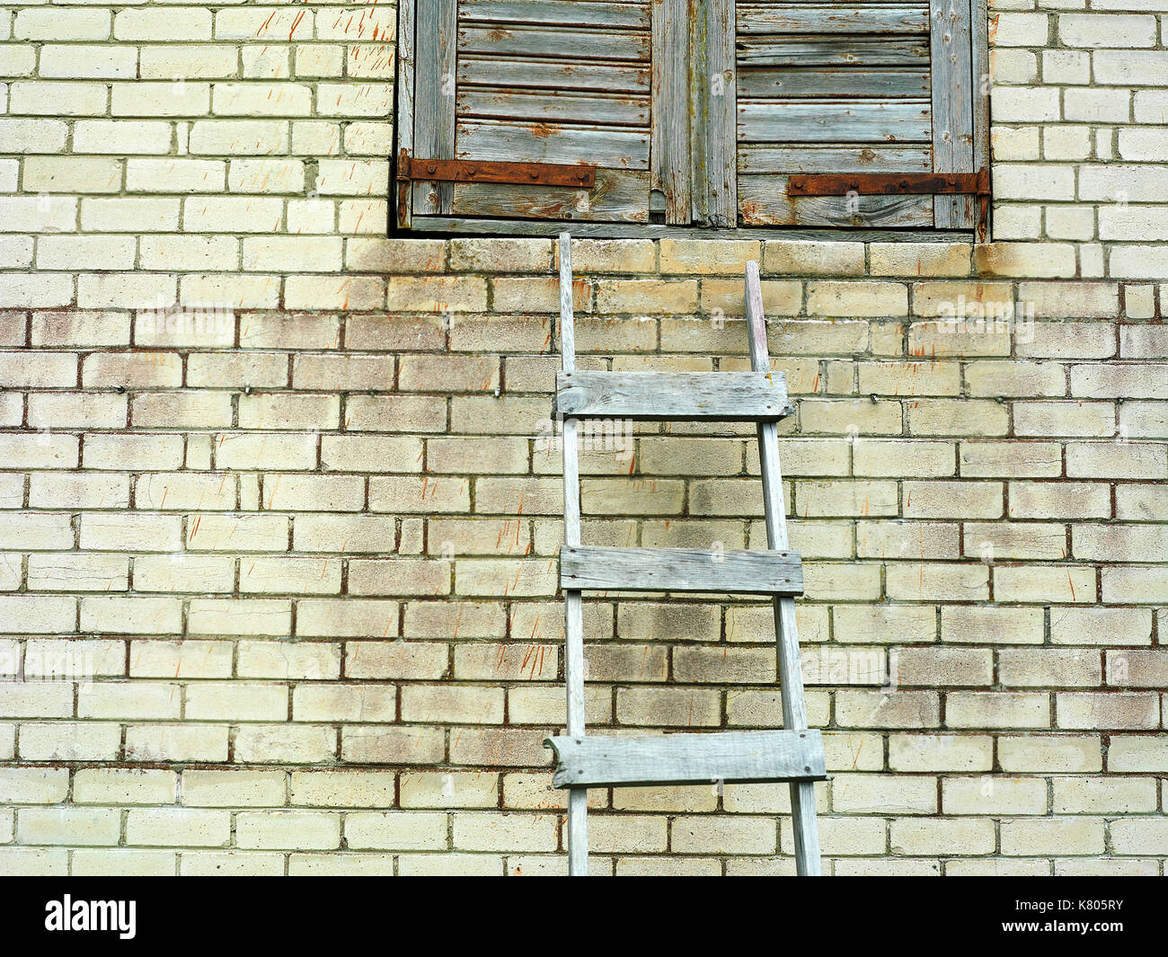 Wooden old ladder against the brick wall heading to closed window ...