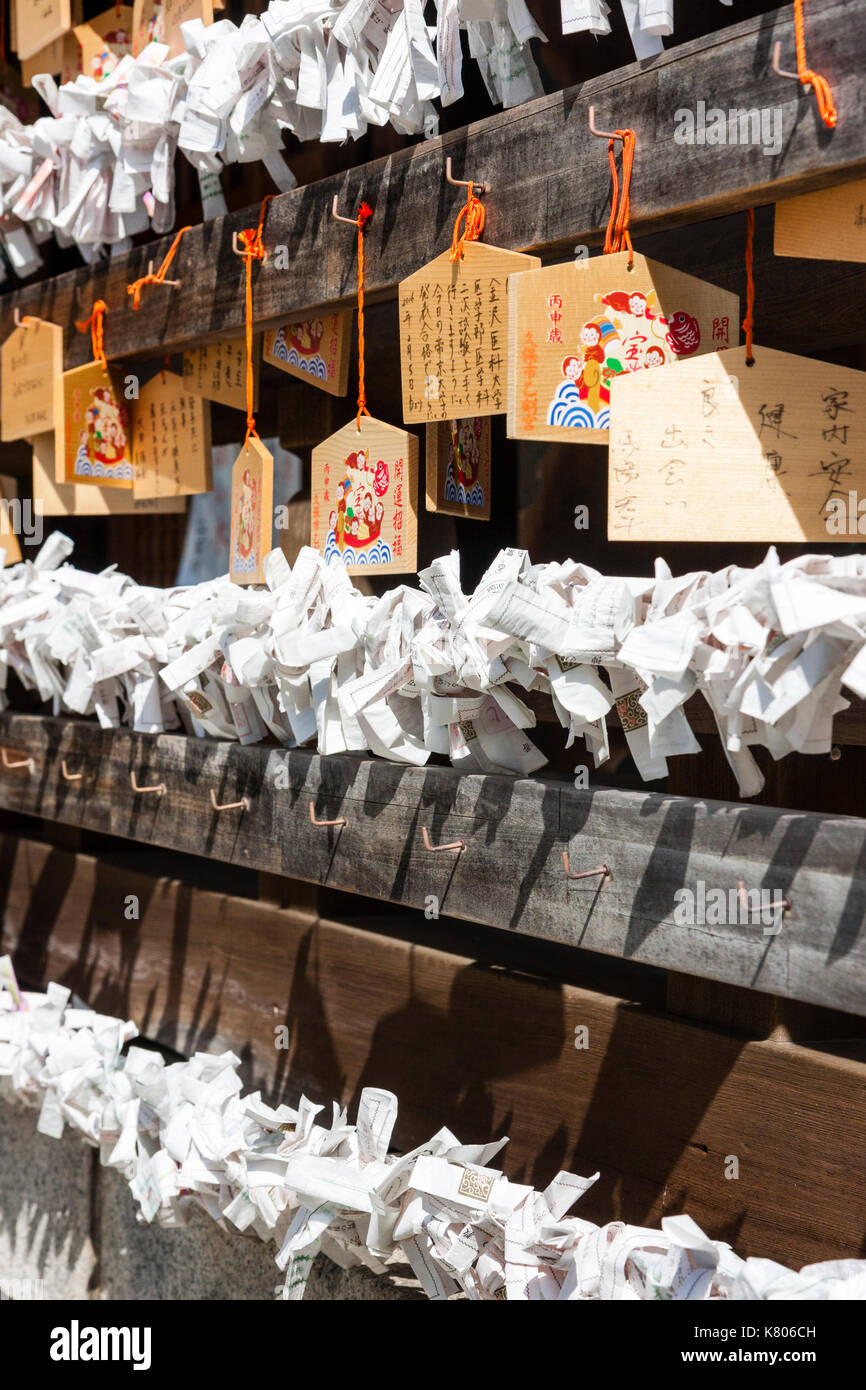 Japan. Ema wooden tablets with Omikuji fortune telling paper slips above and below, hanging from ...