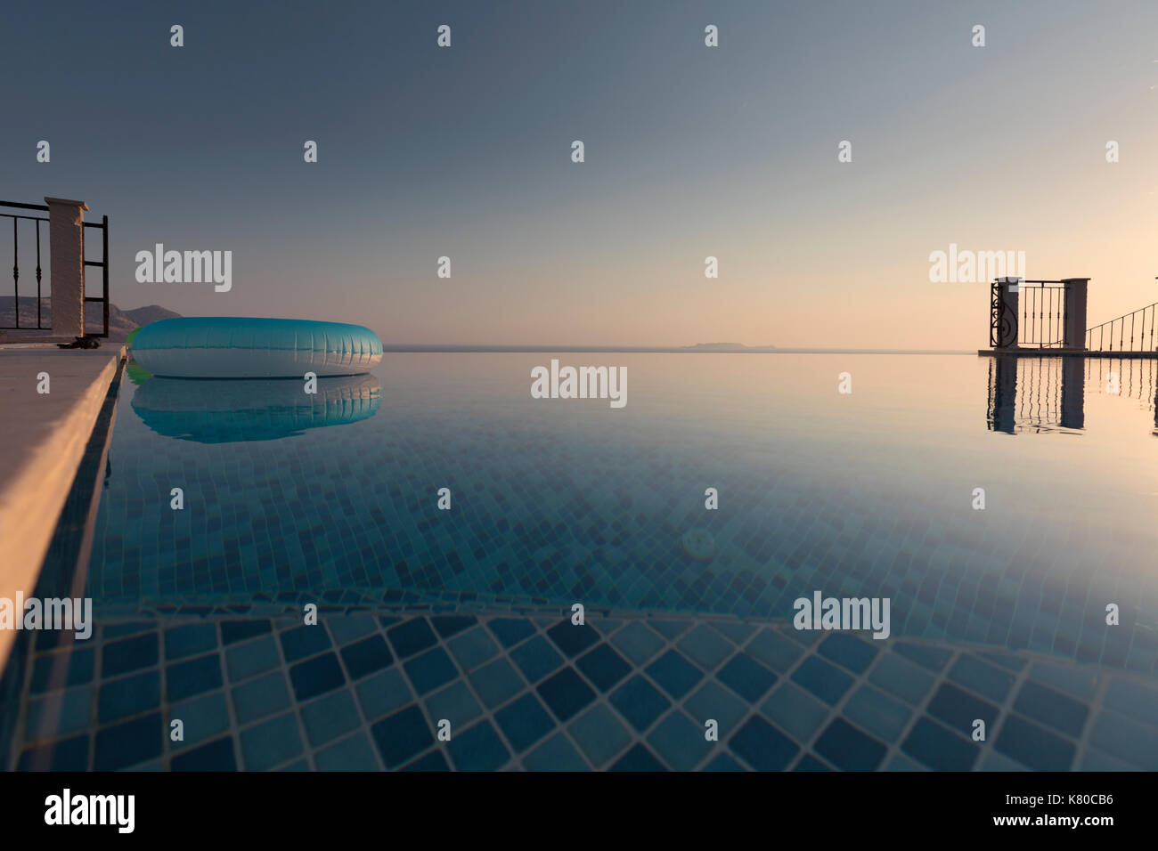 View into distance across infinity pool with lie lows and rings and sun ...