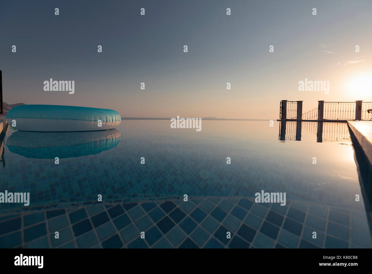 View into distance across infinity pool with lie lows and rings and sun ...