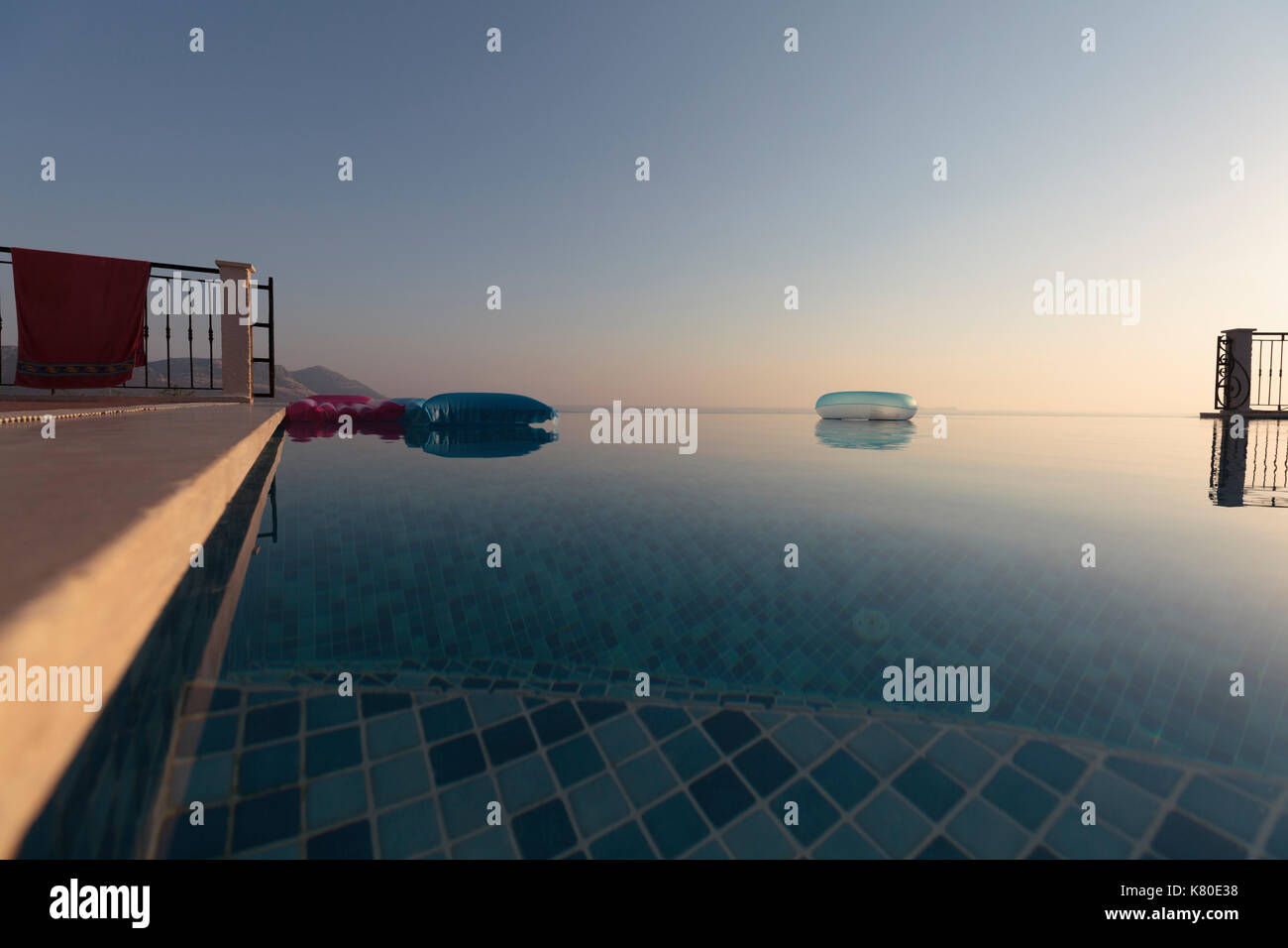 View into distance across infinity pool with lie lows and rings and sun ...