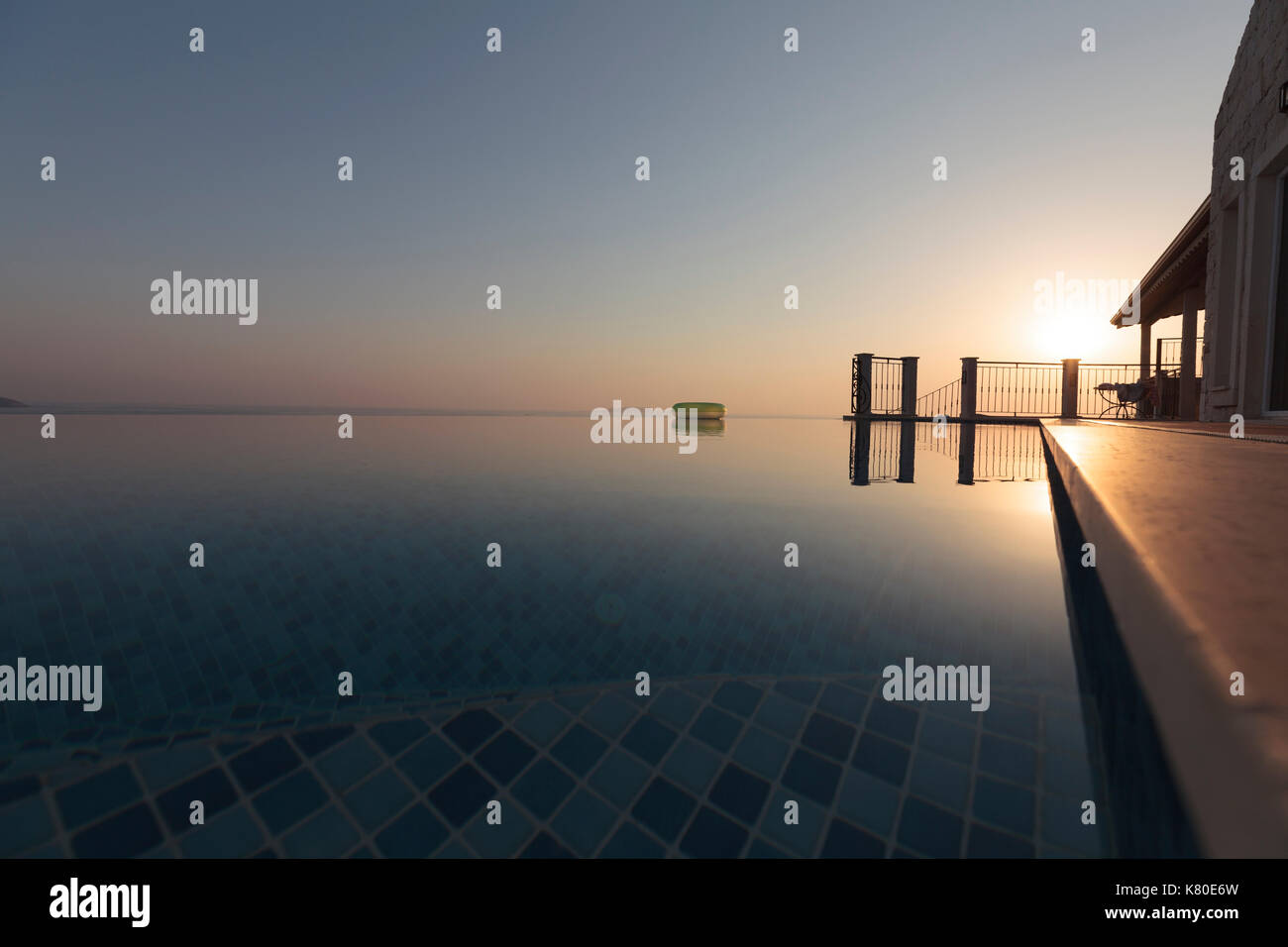 View into distance across infinity pool with lie lows and rings and sun ...