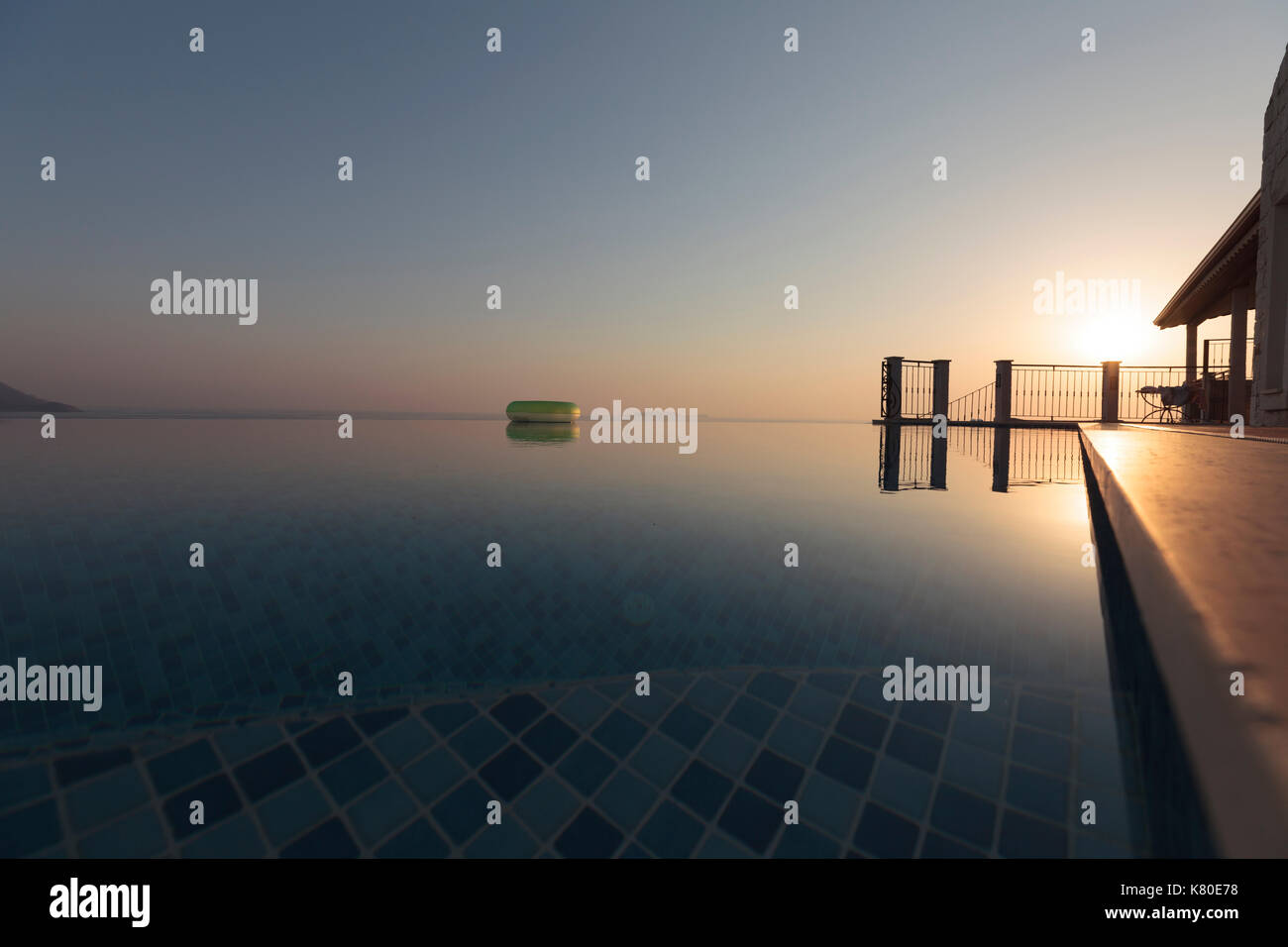 View into distance across infinity pool with lie lows and rings and sun ...