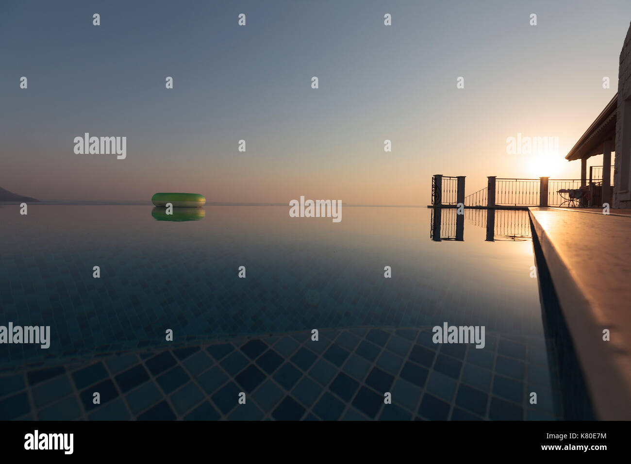 View into distance across infinity pool with lie lows and rings and sun ...