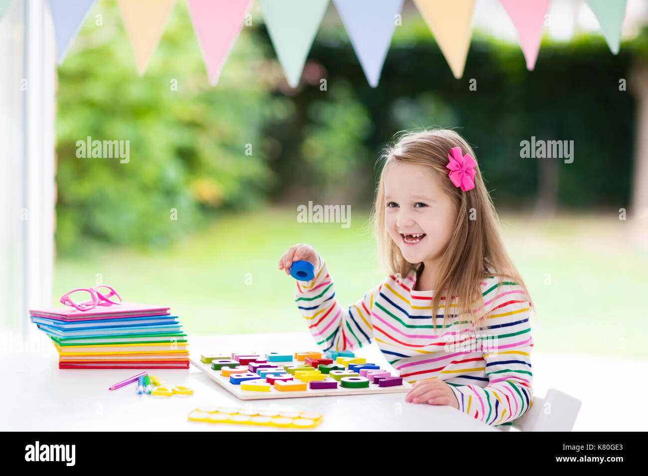 Child doing homework for school at white desk. Wooden educational abc ...