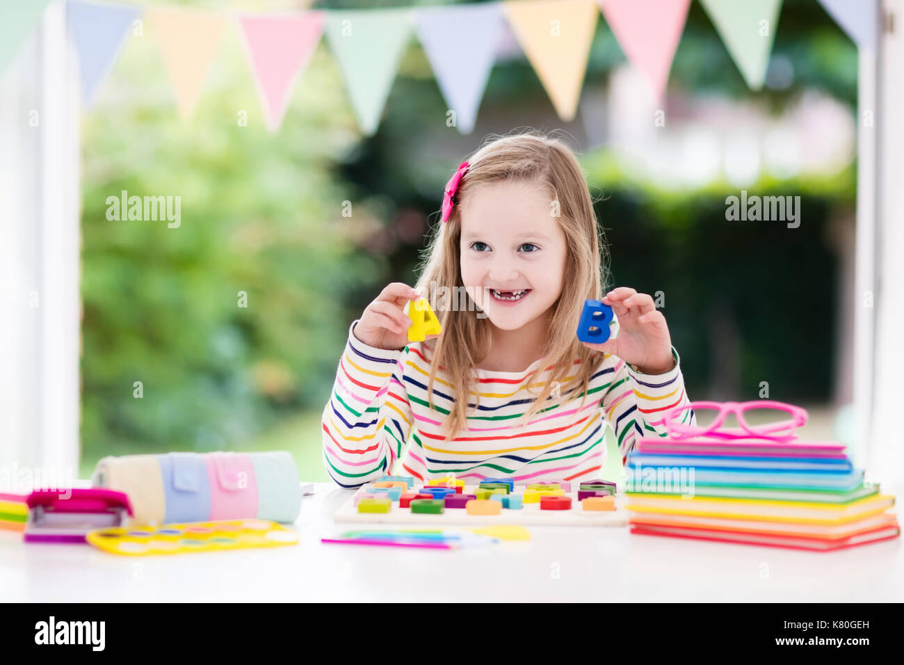 Child doing homework for school at white desk. Wooden educational abc ...