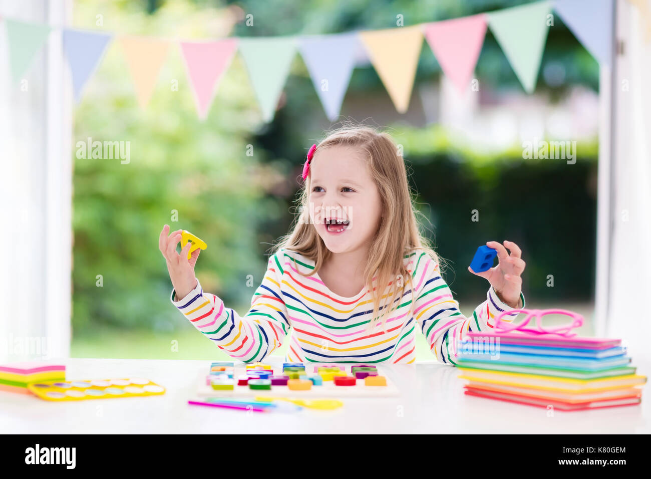 Child doing homework for school at white desk. Wooden educational abc ...
