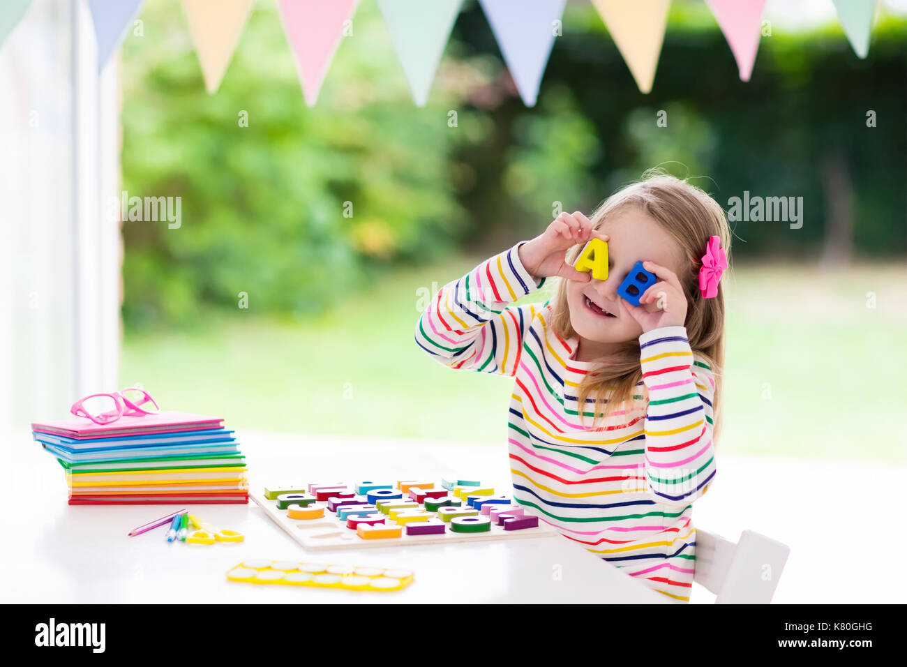 Child doing homework for school at white desk. Wooden educational abc ...
