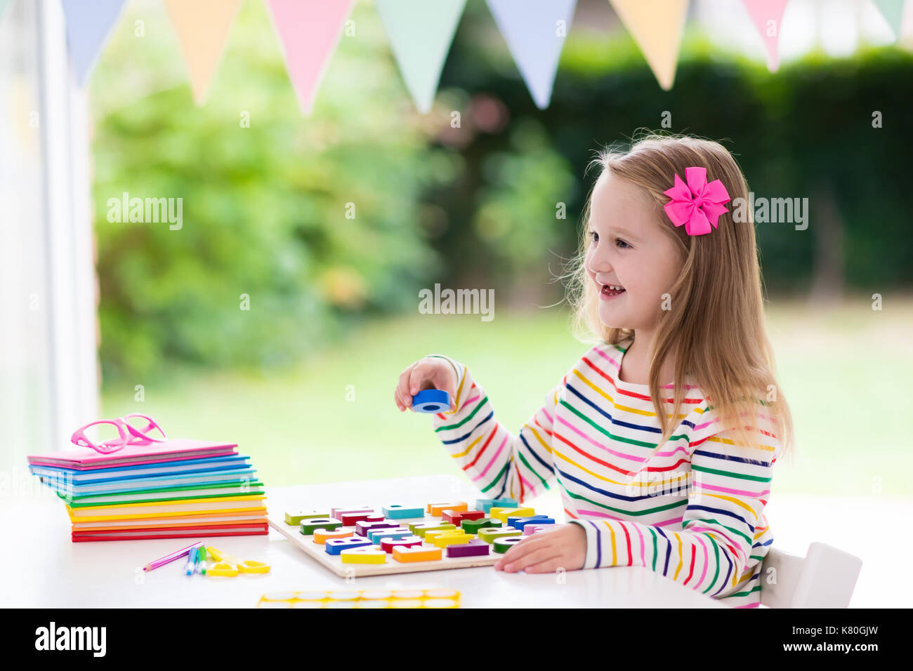 Child doing homework for school at white desk. Wooden educational abc ...