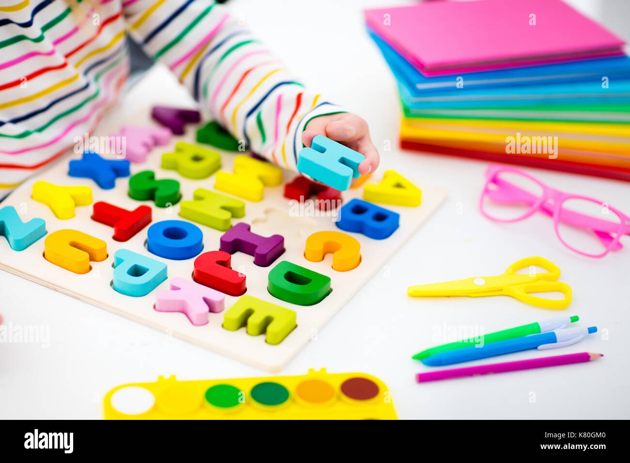 Child doing homework for school at white desk. Wooden educational abc ...