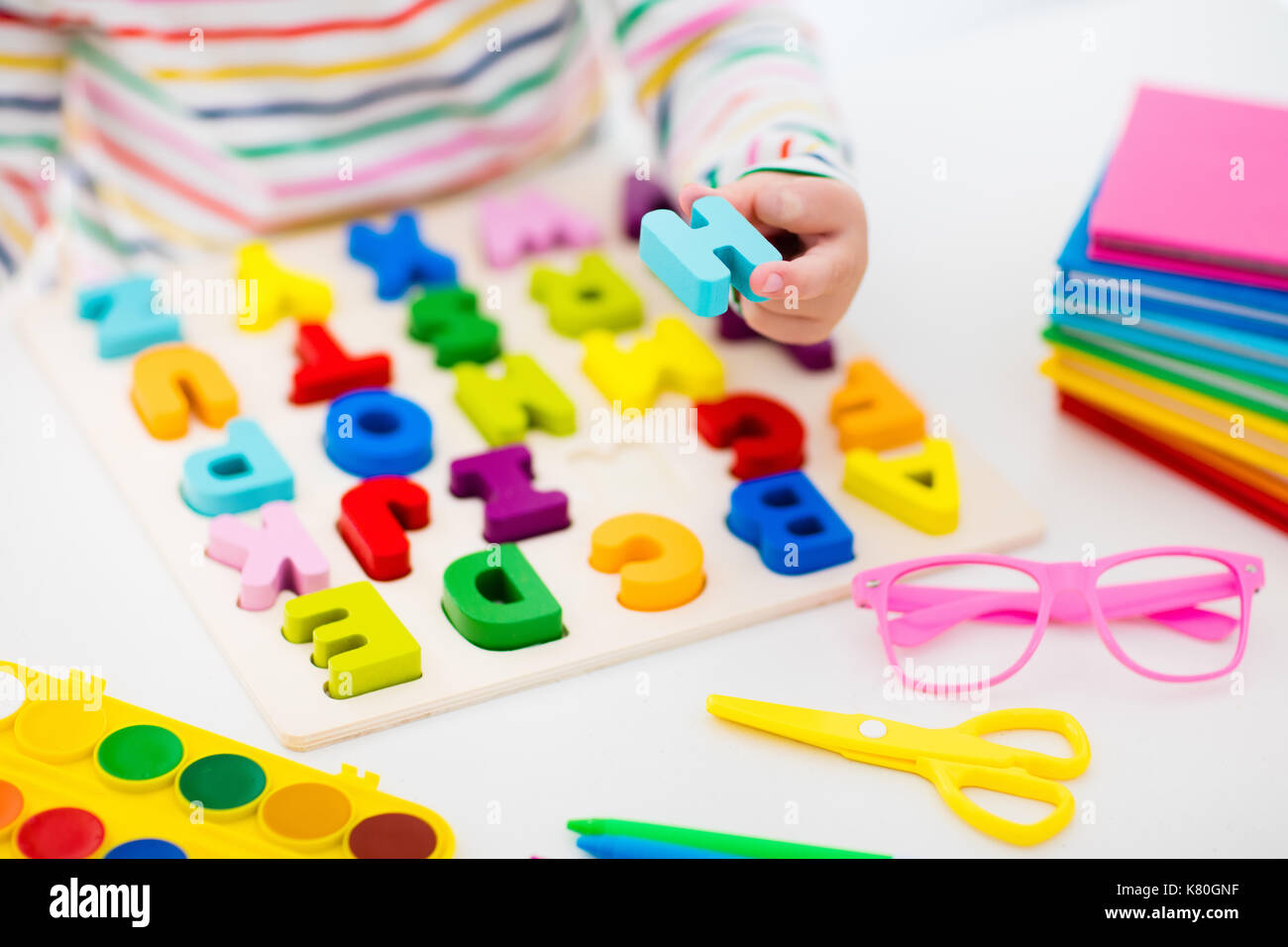 Child doing homework for school at white desk. Wooden educational abc ...