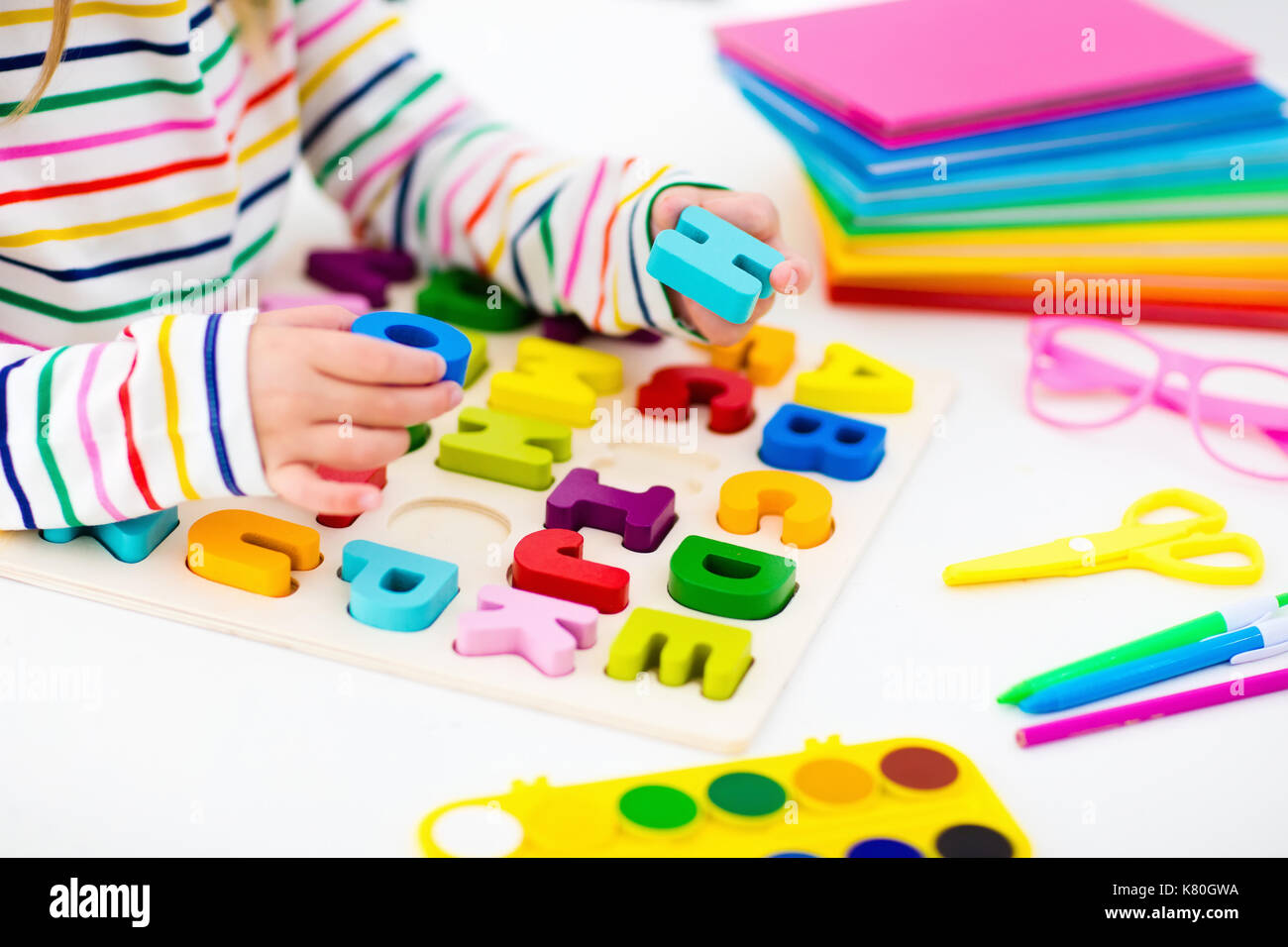 Child doing homework for school at white desk. Wooden educational abc ...