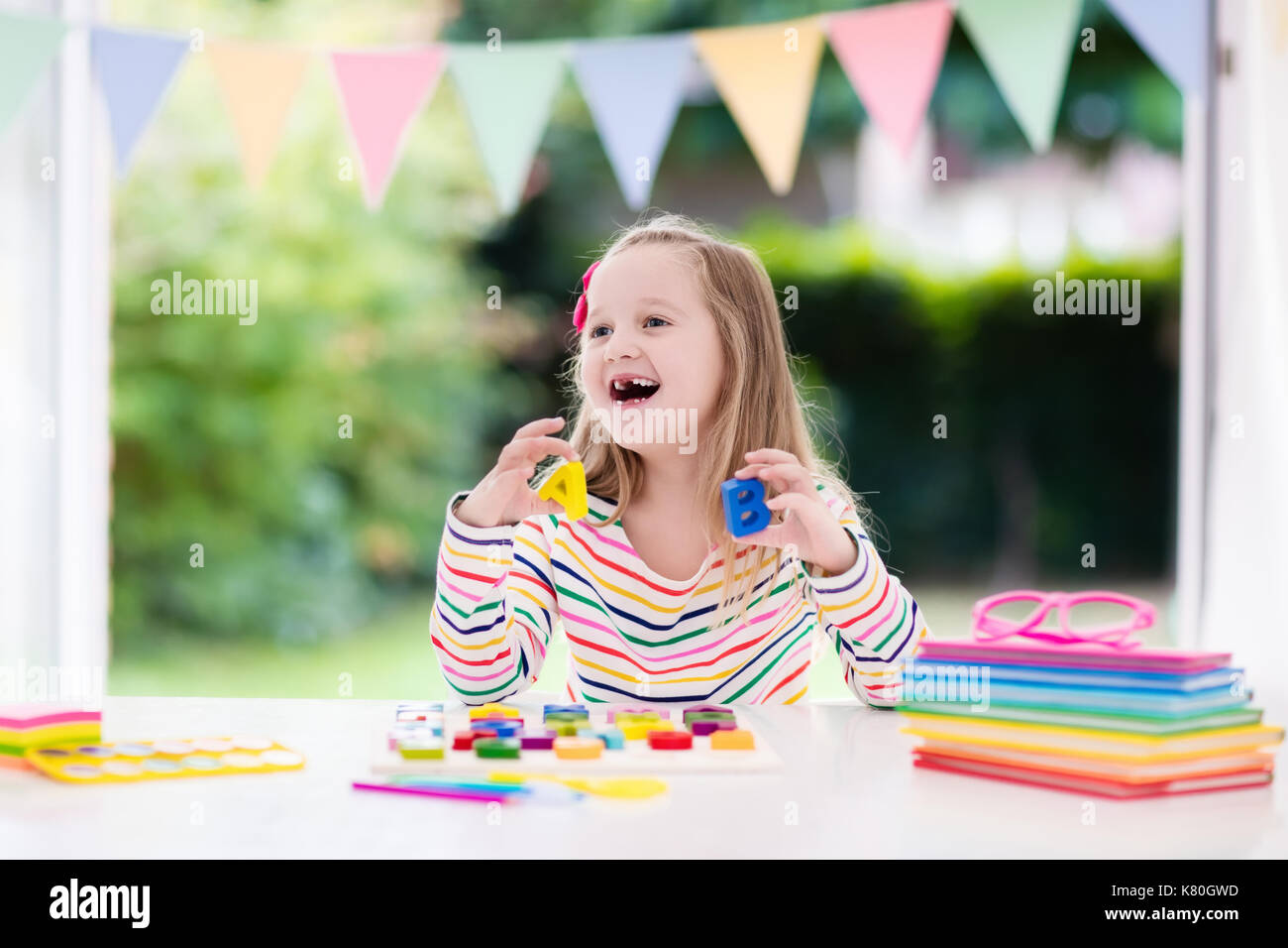 Child doing homework for school at white desk. Wooden educational abc ...