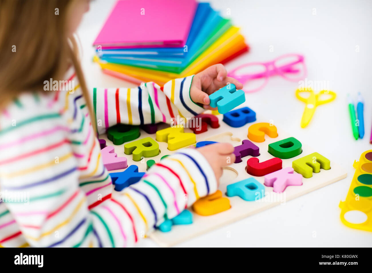 Child doing homework for school at white desk. Wooden educational abc ...