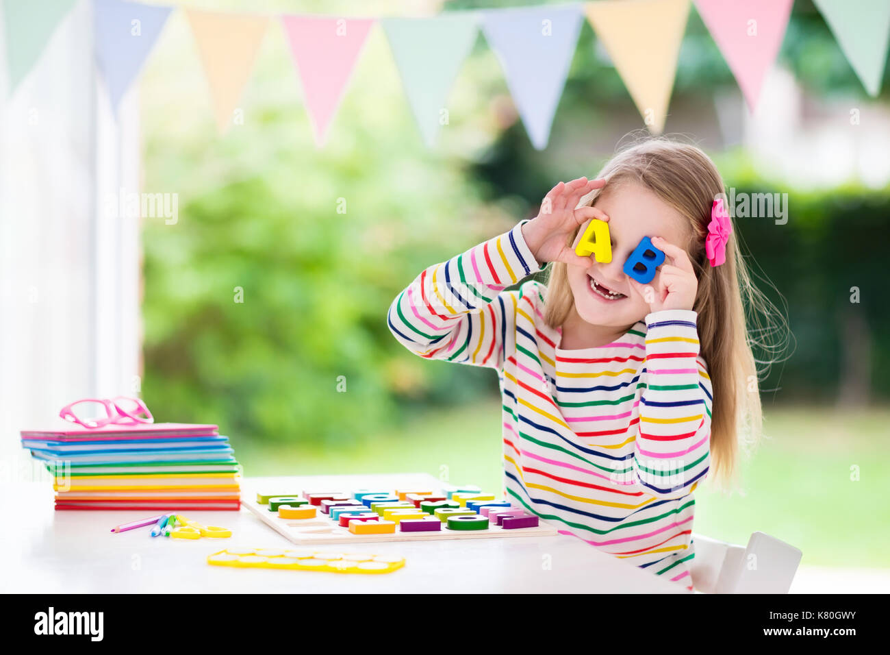 Child doing homework for school at white desk. Wooden educational abc ...