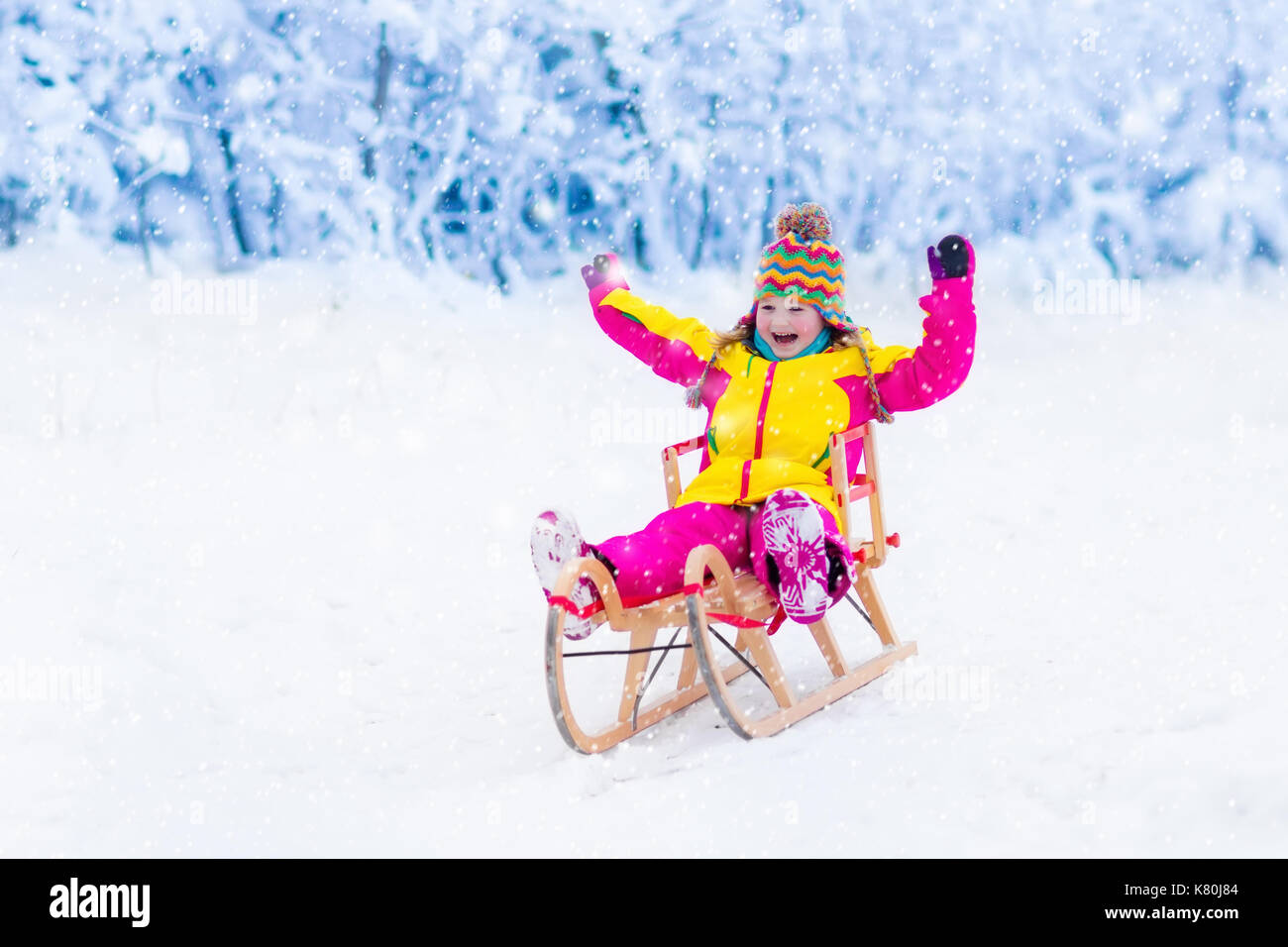 Little girl enjoying a sleigh ride. Child sledding. Toddler kid riding ...
