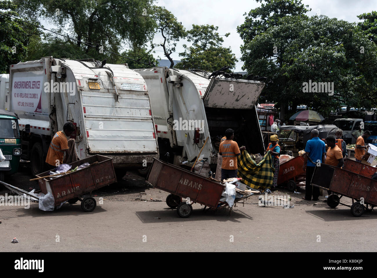 Market stall holders clean up their rubbish (garbage) into waiting dust ...