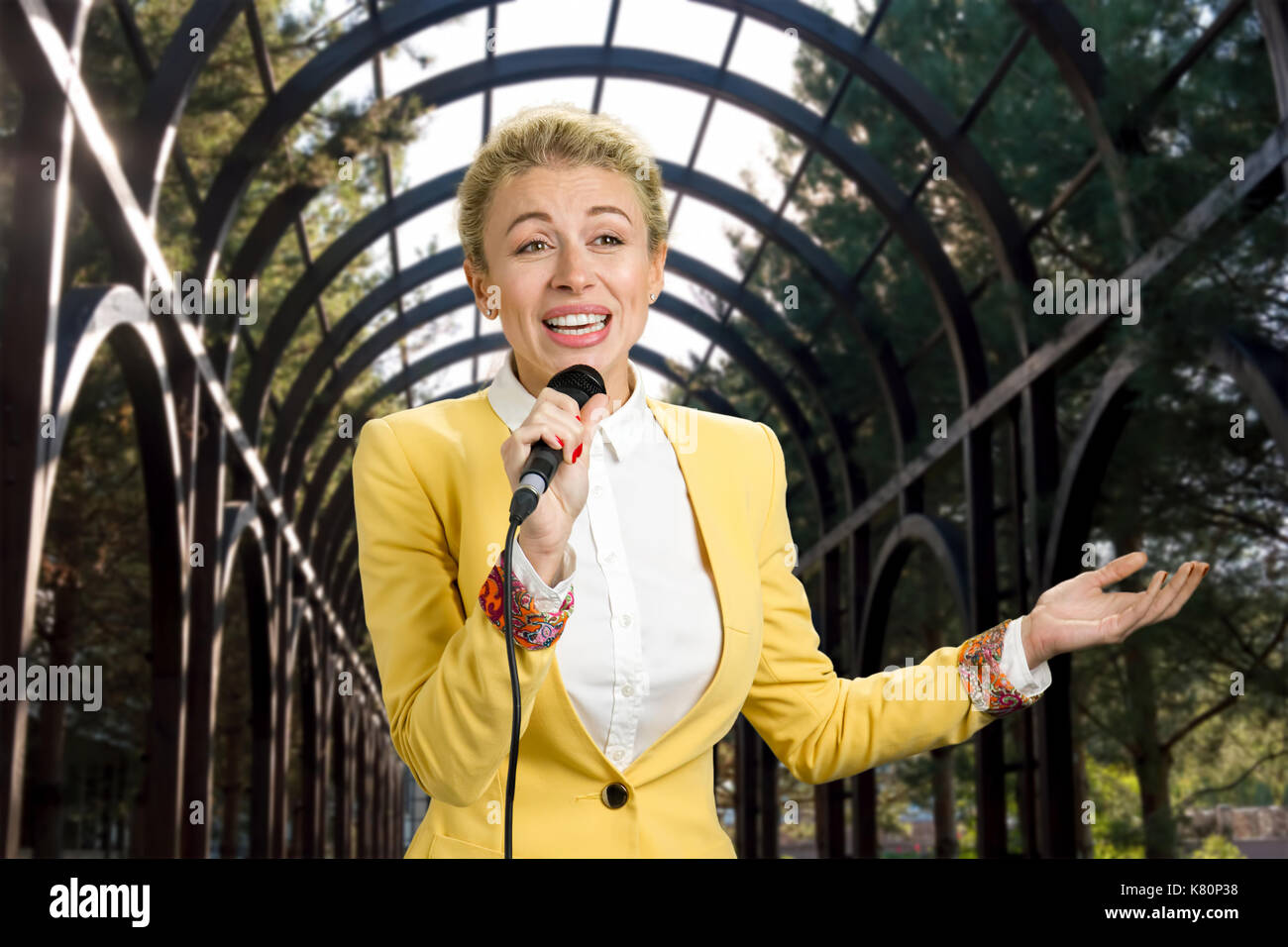Gesturing business woman singing into microphone Stock Photo - Alamy