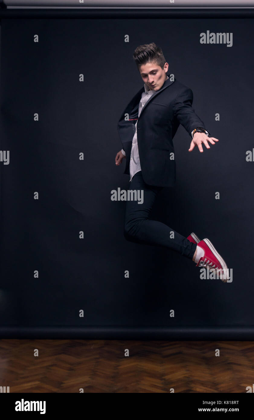 one young teenage boy, black background, studio, fancy jumping in air ...