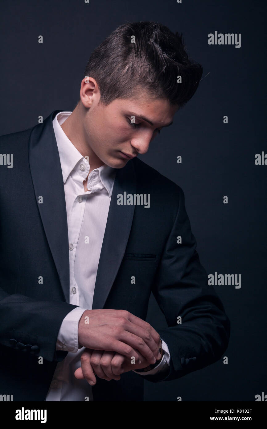 one young teenage boy, looking at watch, black background Stock Photo ...