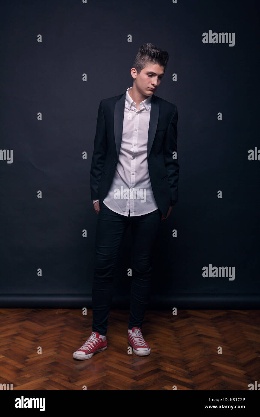 one young teenage boy, black background, studio, looking down, sad ...