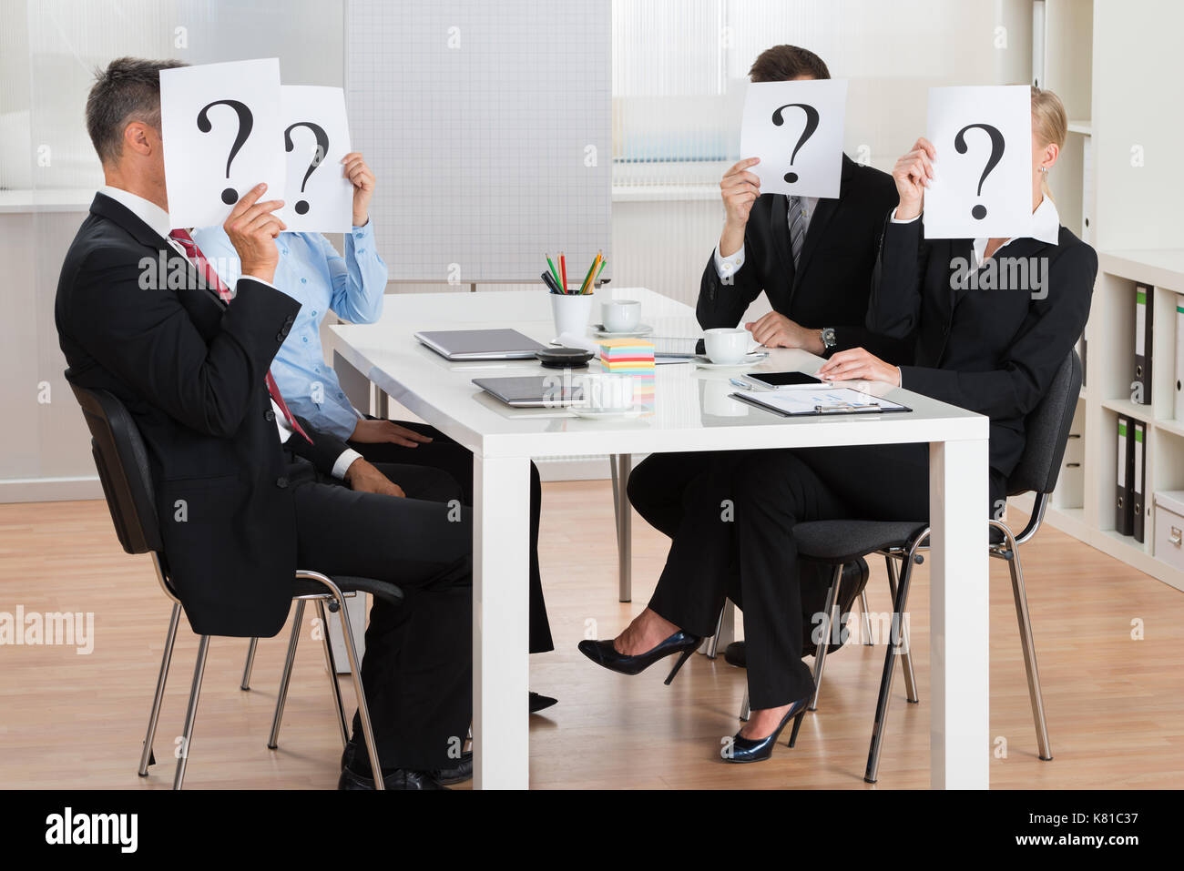 Group Of Businesspeople Hiding Faces Behind Question Mark Sign In ...