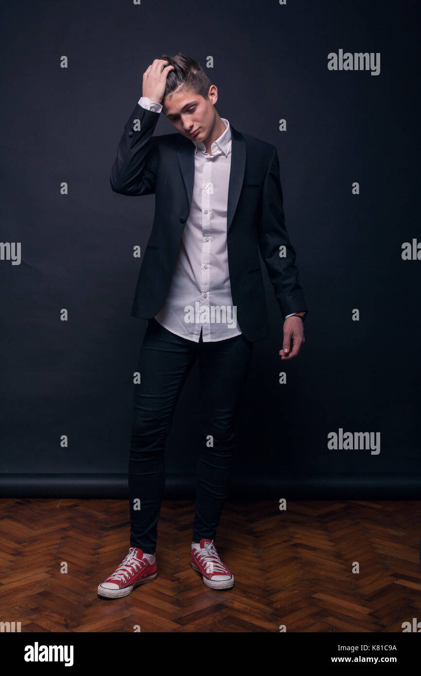 one young teenage boy, black background, studio, looking down, posing ...
