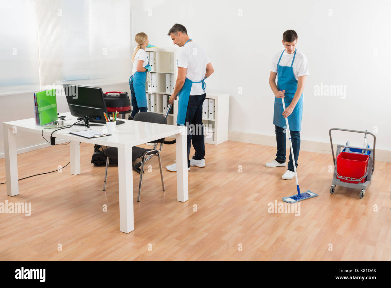 Group Of Three Janitors Together Cleaning Modern Office Stock Photo - Alamy