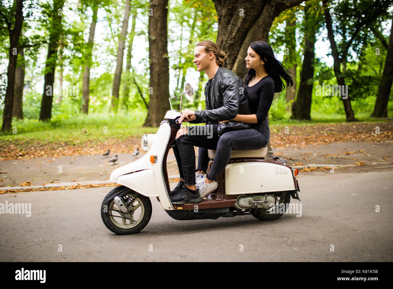 Beautiful young couple riding scooter together, woman hugging her ...