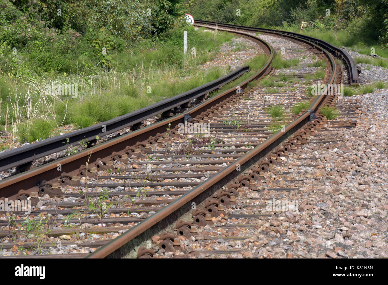 a rusty railway track going round a corner and disappearing into a ...