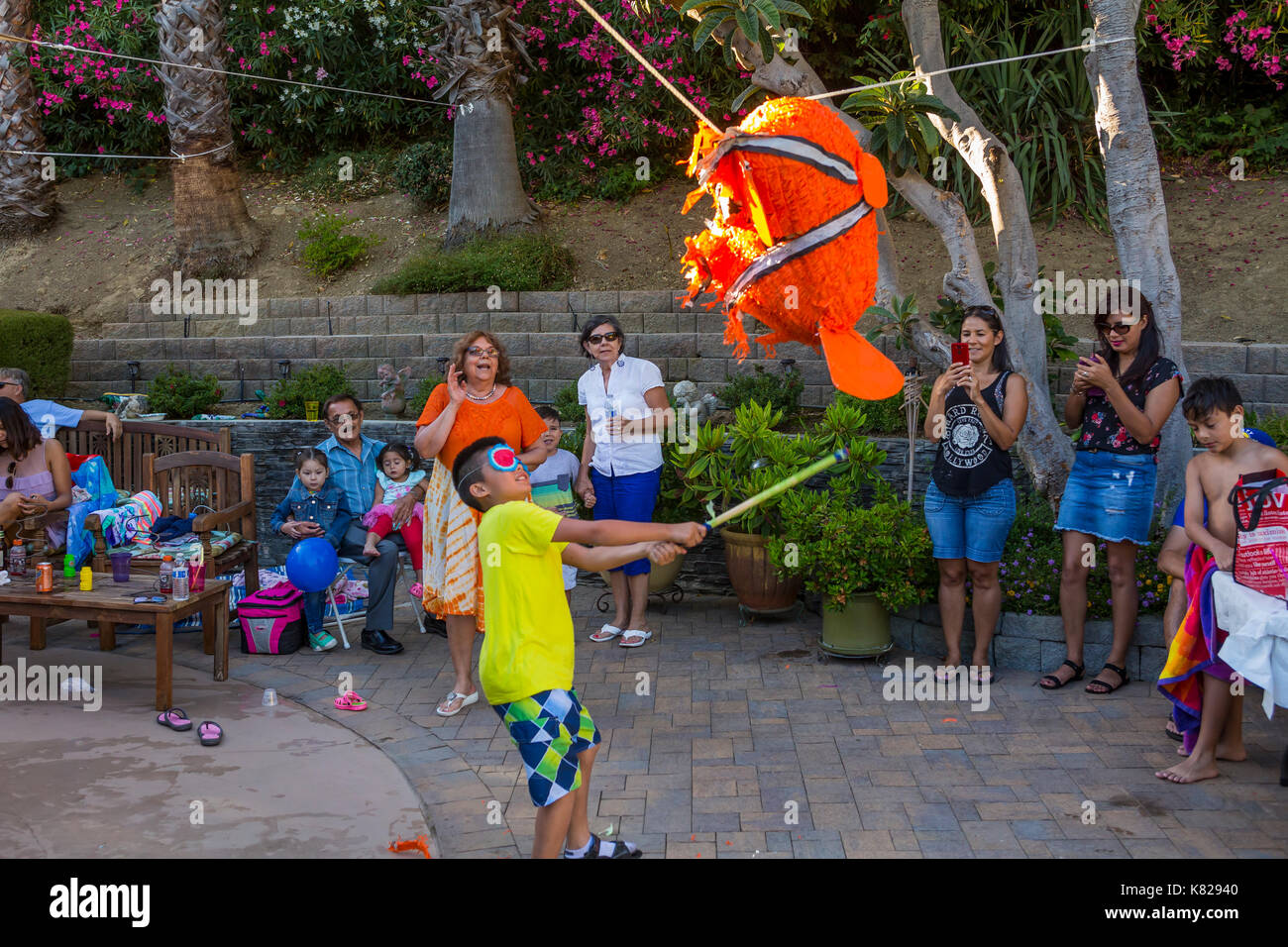 Hispanic boy, hitting a pinata, pinata filled with candy sweets and ...